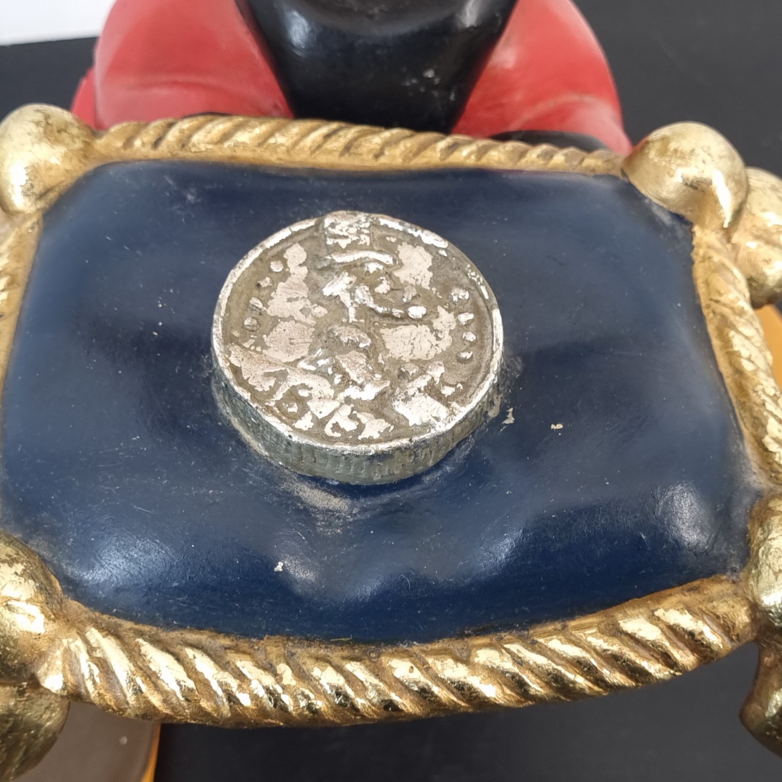 Scrooge McDuck with his lucky dime on a pillow statue