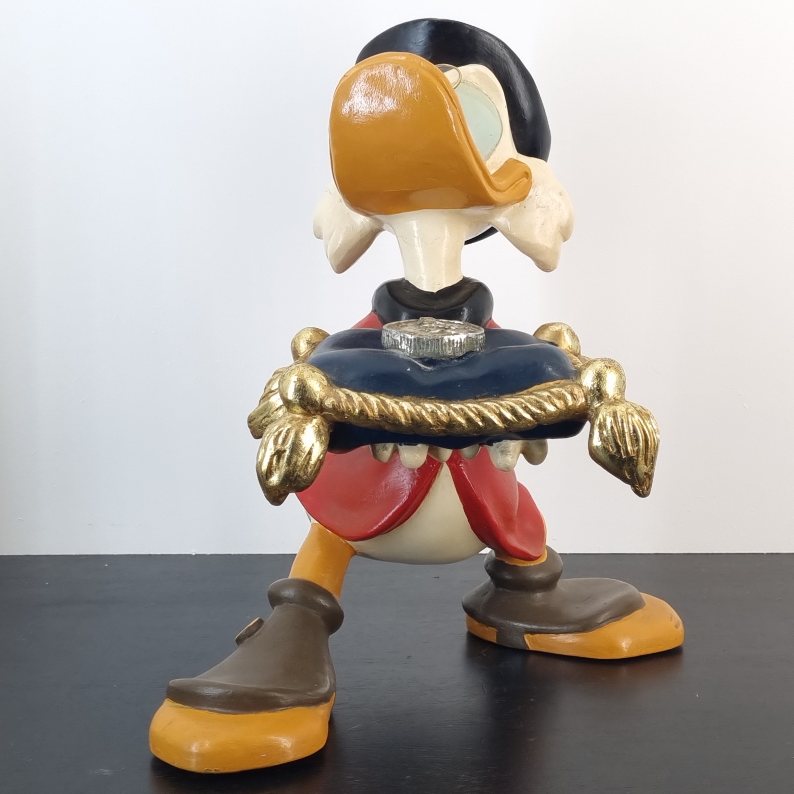 Scrooge McDuck with his lucky dime on a pillow statue