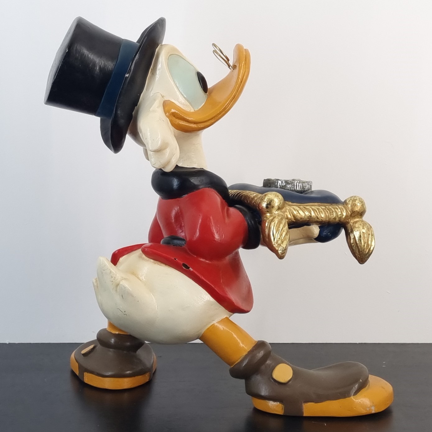 Scrooge McDuck with his lucky dime on a pillow statue