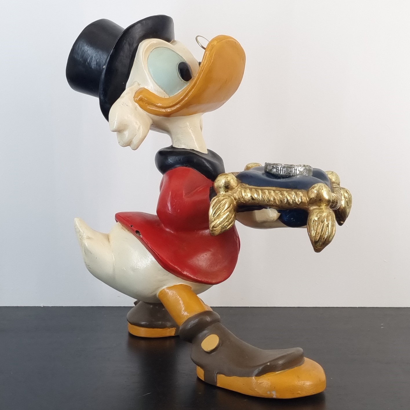 Scrooge McDuck with his lucky dime on a pillow statue